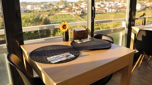 Uma mesa de jantar com vista para uma cidade, um vaso com um girassol e uma caixa de Complan.
