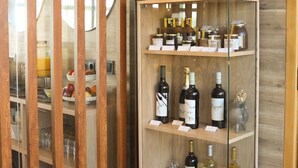 Exposição de vinhos e café em um interior de madeira, com uma obra de arte moderna na parede.