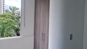 Quarto nos cantos com uma janela grande, um guarda-roupa e chão ladrilhado.