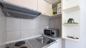 Uma cozinha compacta com uma pia de aço inoxidável, micro-ondas e fogão a gás.