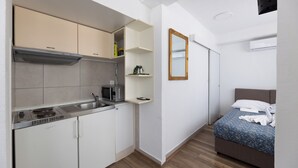 Quarto compacto com cozinha compacta, uma cama e um espelho.