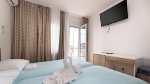 Quarto de hotel com cama, escrivaninha, televisão e vista para o exterior.