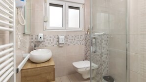 Casa de banho moderna com cabine de duche em vidro, lavatório branco e sanita.