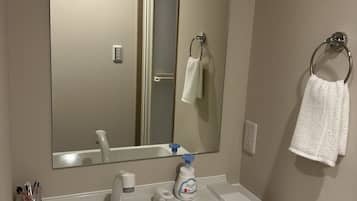 Casa de banho com lavatório branco, espelho e porta-toalhas.