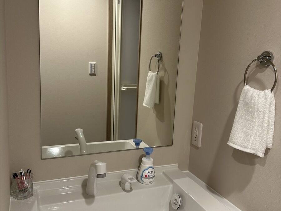 Casa de banho com lavatório branco, espelho e porta-toalhas.