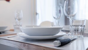 Uma mesa de jantar com uma tigela branca, uma faca e um copo d'água.