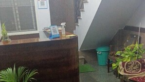 Uma área de recepção com balcão, escada e plantas em vasos.