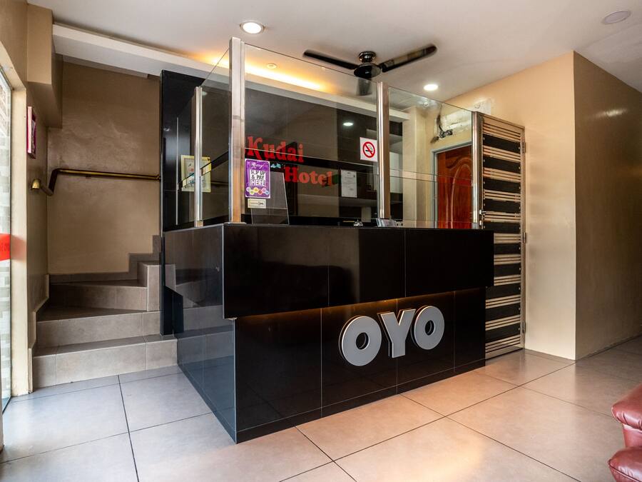 Bancada de recepção com divisória de vidro, placa de 'Não Fumar' e placa com o nome 'Kuda Hotel'.