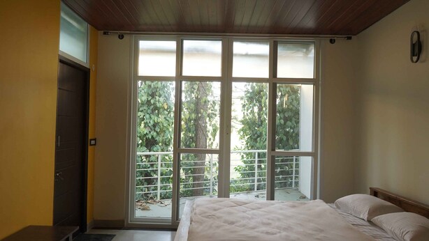 Quarto com uma janela grande, uma cama e um banco.