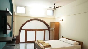 Quarto com cama de madeira, guarda-roupa, escrivaninha e janela.