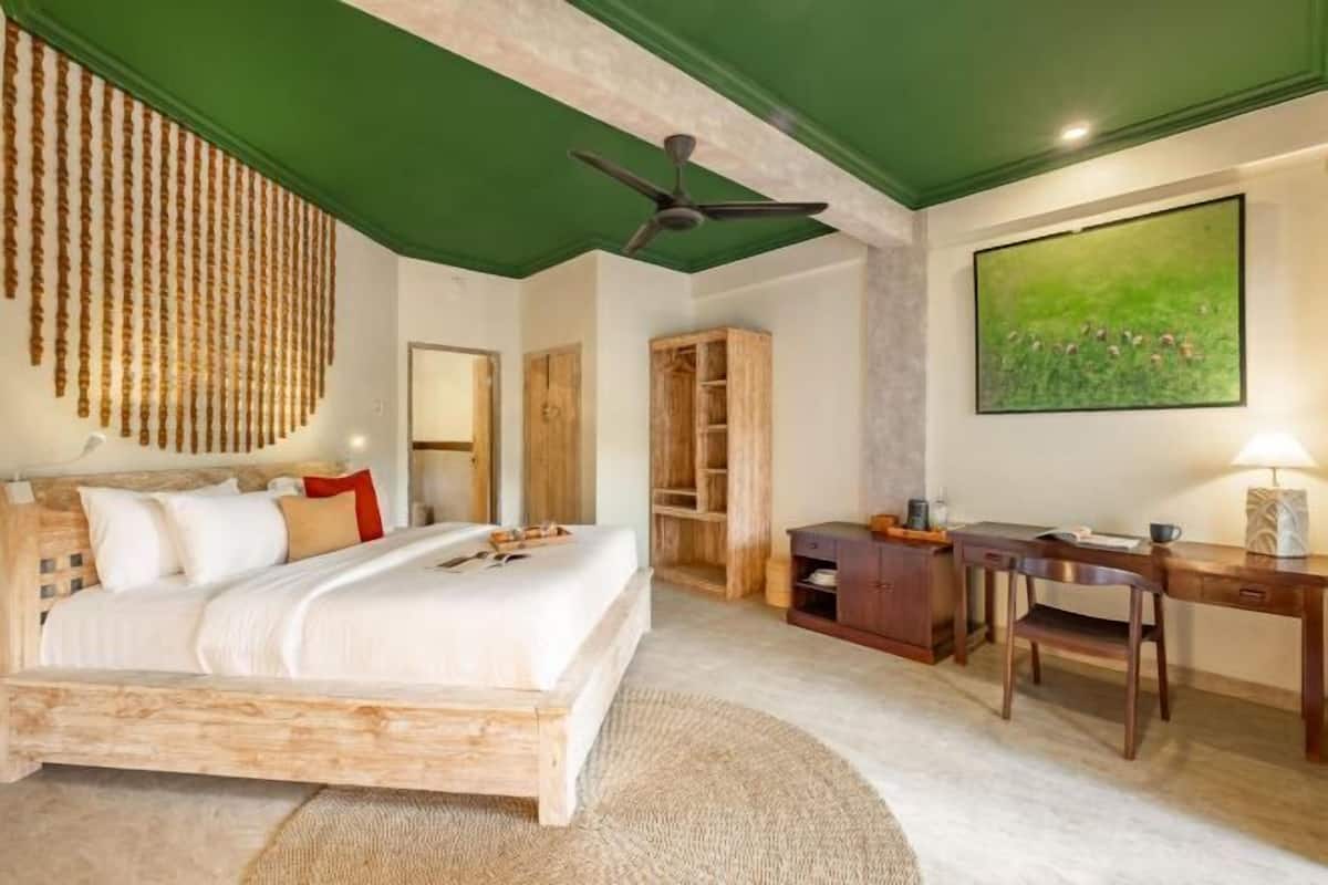 Quarto com cama, escrivaninha, cadeira e um quadro na parede.