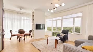 Ampla sala de estar com mesa de jantar, cadeiras, sofá e televisão fixada na parede.