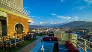 Área de piscina no terraço, com vista para a cidade e montanhas.