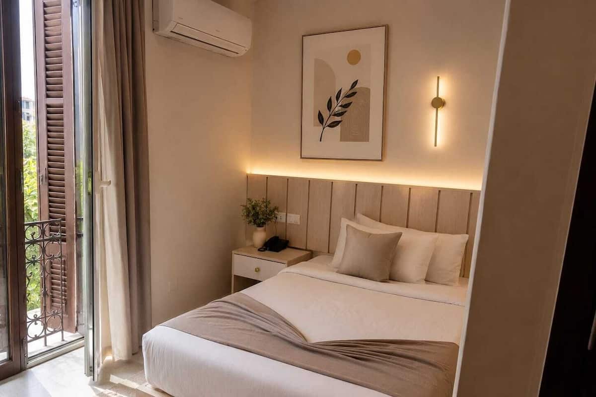 Quarto com cama, mesa de cabeceira, luminária e obra de arte.