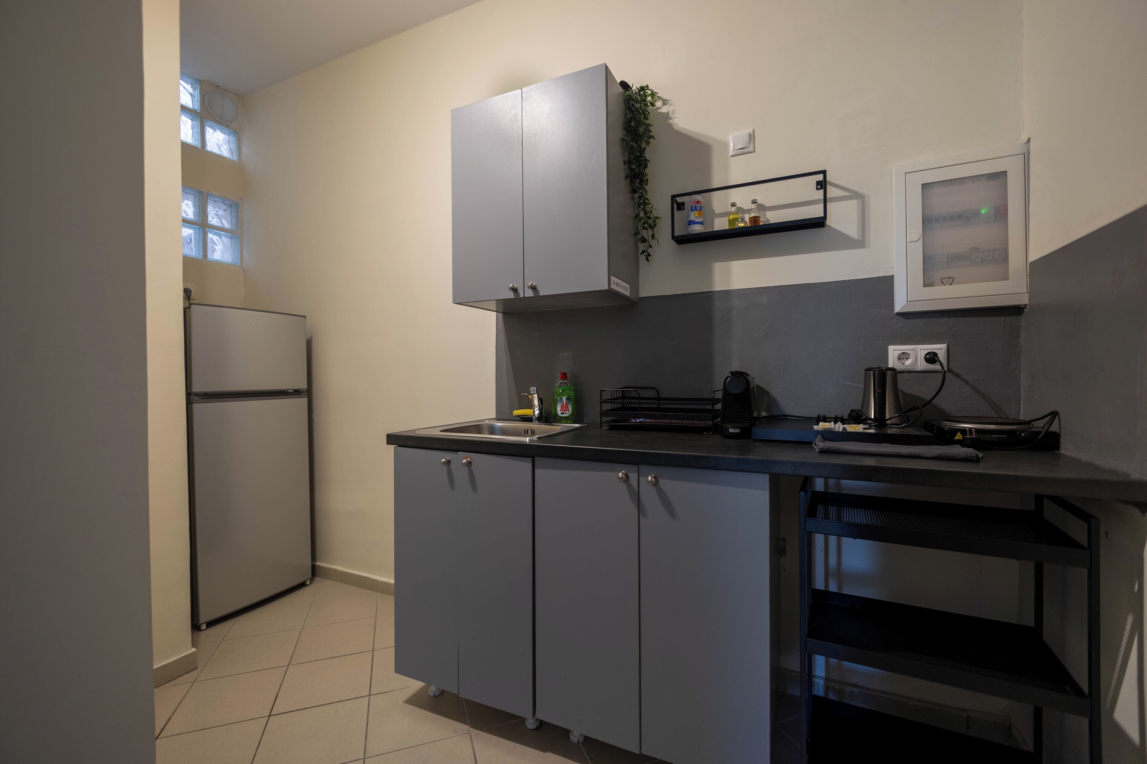 Uma cozinha compacta com armários cinza, uma pia embutida e um balcão pequeno.