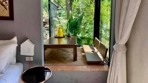 Quarto com porta de vidro que dá para uma varanda com vista para o verde.