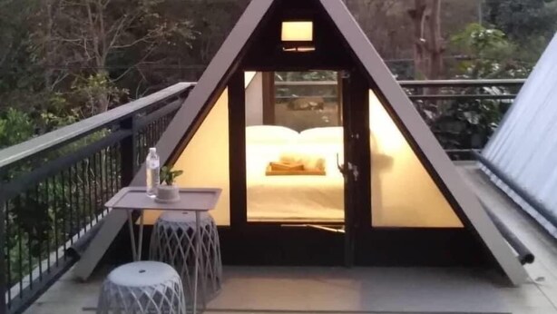 Uma estrutura em formato de A com cama e uma mesa com uma cadeira.