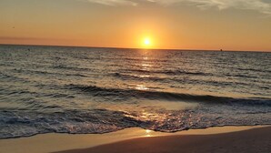 Cena de praia com ondas e um pôr do sol.