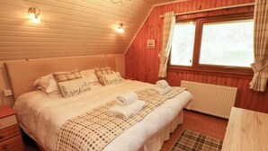 Um quarto acolhedor com uma cama grande, uma mesa de cabeceira, um radiador e uma janela com cortinas.