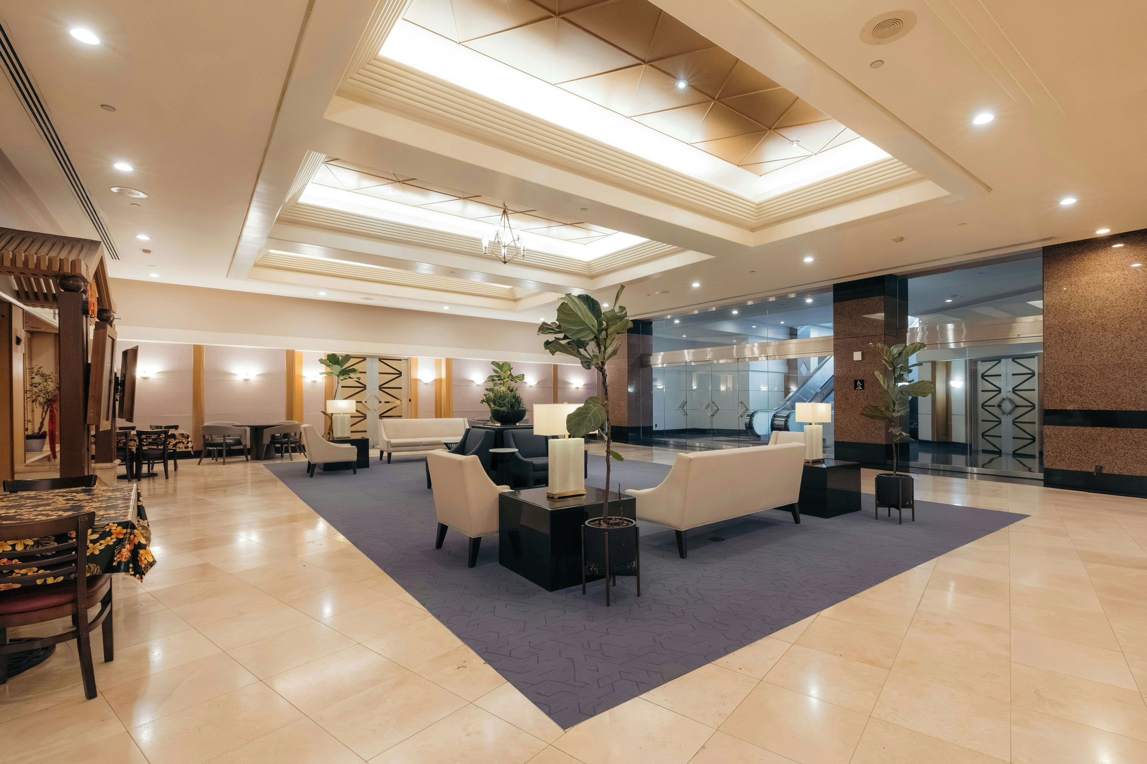 Um hall amplo com área de estar central, balcão de recepção e design de teto moderno.
