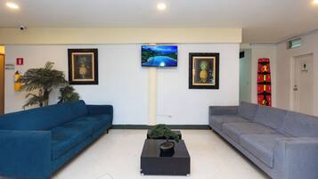 Uma área de recepção com dois sofás, uma mesa de centro e quadros nas paredes.