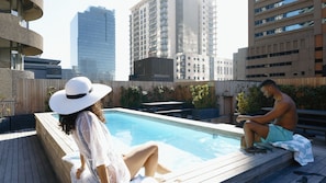 Uma área de piscina no terraço com vista para edifícios altos ao redor.