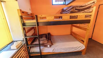 Uma cama beliche com escada, uma janela com cortinas e um radiador.