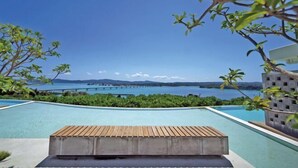 Piscina com deck de madeira e vista para uma ponte sobre a água.