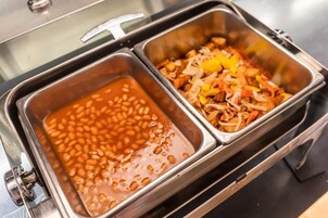 Buffet com dois recipientes: um com feijão cozido e outro com um prato misto de carne e legumes.