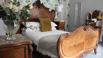 Quarto com cama de madeira, mesa de cabeceira, espelho e papel de parede floral.