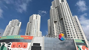 Um edifício alto com design arquitetônico moderno, com várias varandas e fachada de vidro.