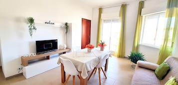 Uma sala de estar moderna com televisão, mesa de jantar e sofá.