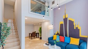 Uma sala de estar moderna com escada, área de jantar e um mural com vista para a cidade.