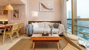 Uma sala de estar moderna com um sofá, uma mesa de jantar com cadeiras, uma mesa de centro e uma grande janela com vista para a cidade.