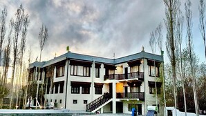 Um edifício com vários andares, varandas, uma escadaria e um gramado bem cuidado.