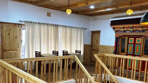 Interior em madeira com escada, área de refeições e estrutura decorativa tradicional.