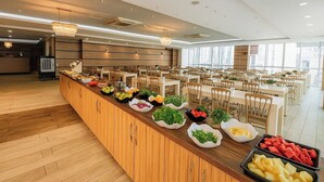 Disposição de buffet com diversos alimentos e área de estar com mesas e cadeiras.