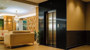 Um hall moderno com balcão de recepção, área de espera com cadeiras e um elevador grande.