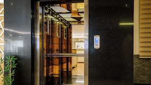 Um elevador com design moderno, apresentando interior metálico e painel de comando com botões de direção.