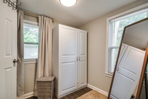 Um corredor com uma porta branca, uma cesta de vime e um guarda-roupa branco.