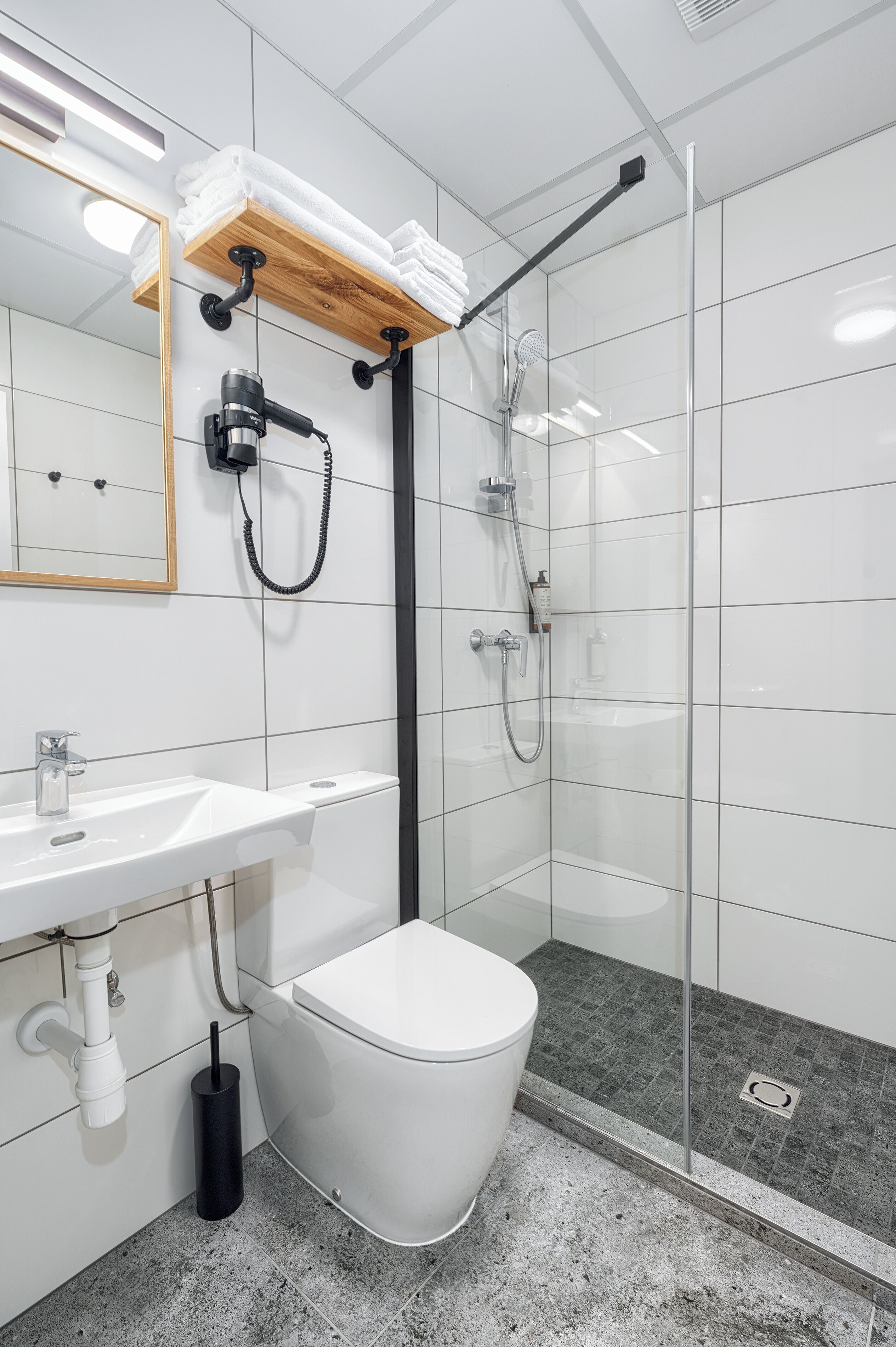 Casa de banho moderna com lavatório branco, sanita e cabine de duche em vidro.