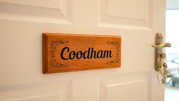 Placa de madeira com o nome 'Goodham' fixada numa porta branca.