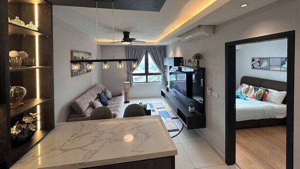 Uma sala de estar moderna com sofá, TV e uma ilha de mármore.