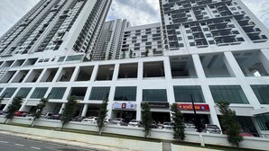 Um edifício moderno de vários andares, com amplas janelas e uma área de estacionamento com carros.