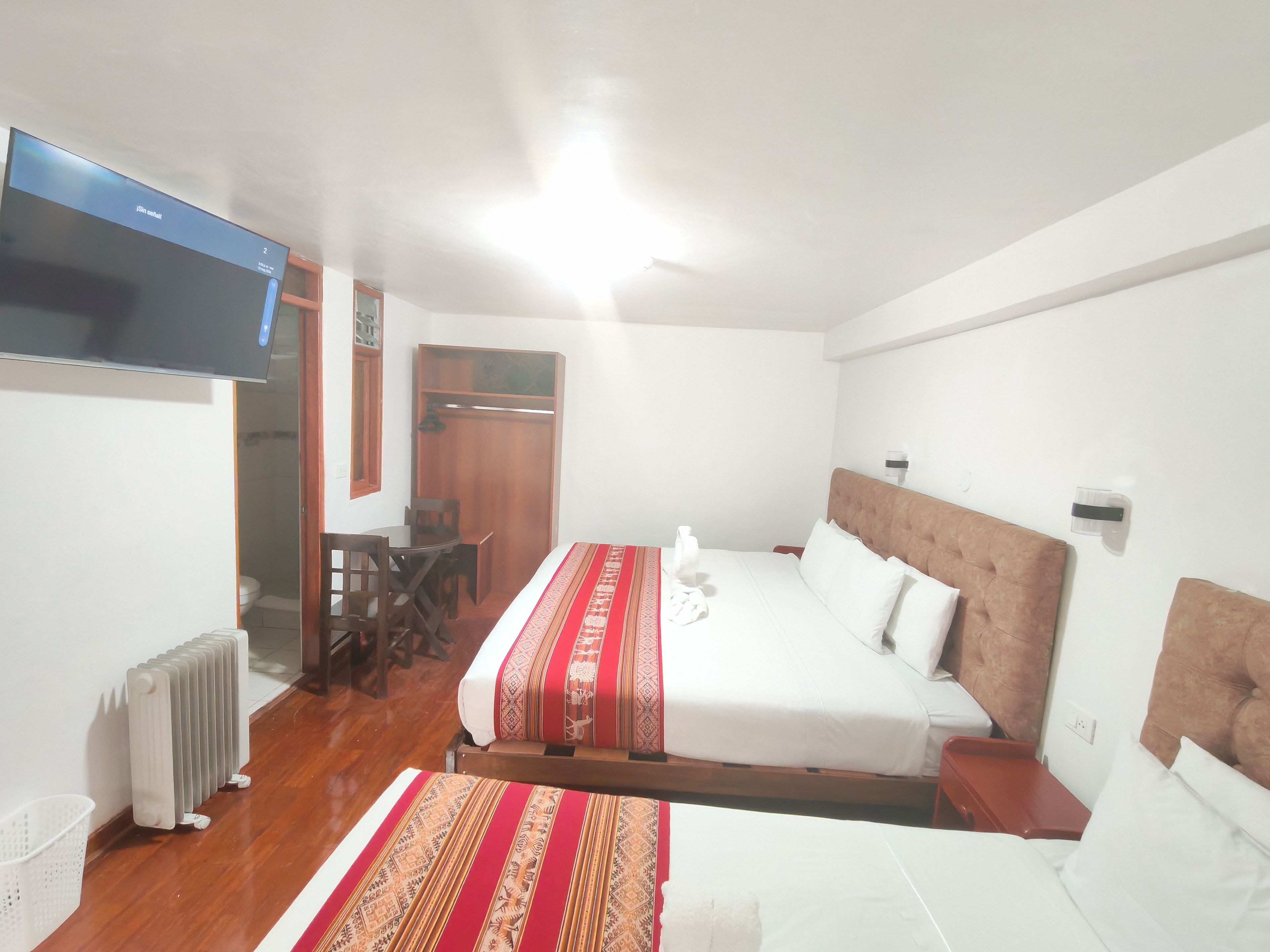 Quarto de hotel com cama, escrivaninha e cadeira.