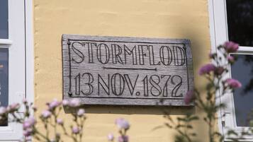 Uma placa de madeira com o texto 'STORMFLOOD 13 NOV. 1872' fixada em uma parede amarela.