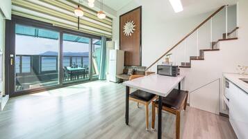 Cozinha moderna com área de refeições, micro-ondas e vista para o mar.