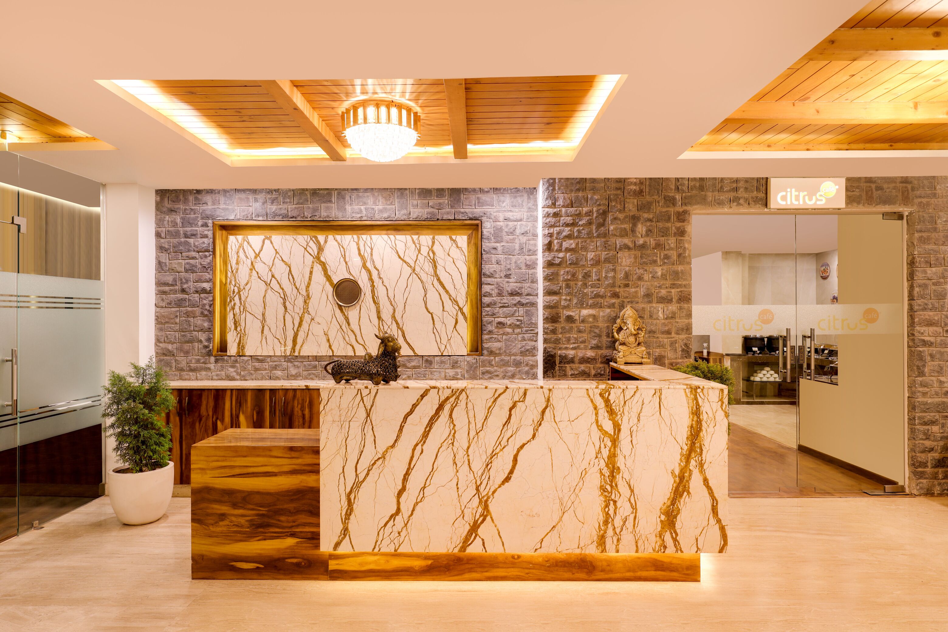 Uma área de recepção com balcão de mármore, lustre e parede de pedra.