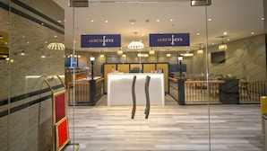 Um lobby de hotel moderno com balcão de recepção, área de estar e divisória de vidro.