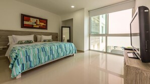 Quarto de hotel moderno com uma cama grande, televisão de tela plana e uma janela ampla com vista para o exterior.
